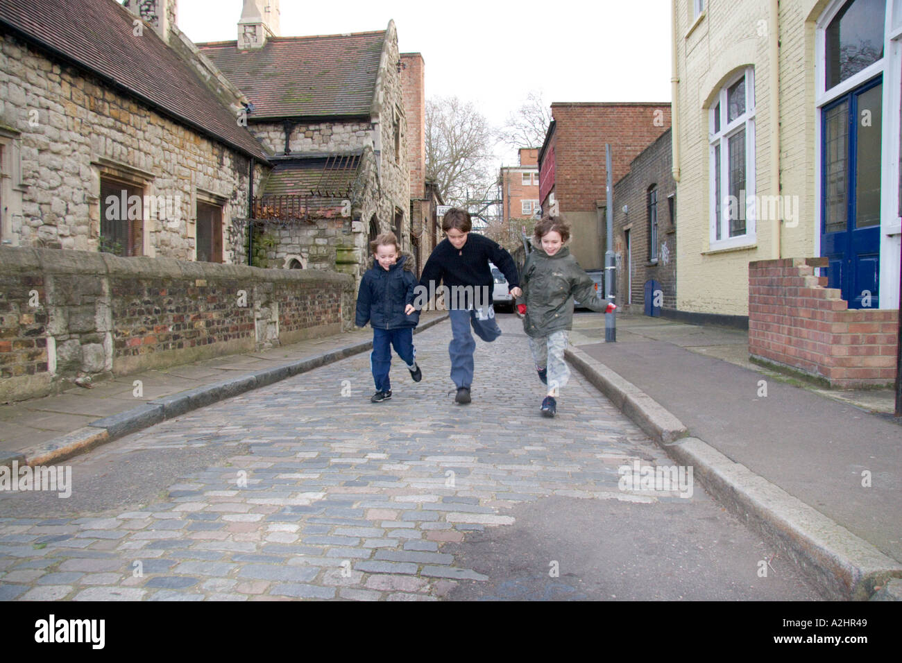 Three happy boys running up a cobbled street model released Stock Photo ...