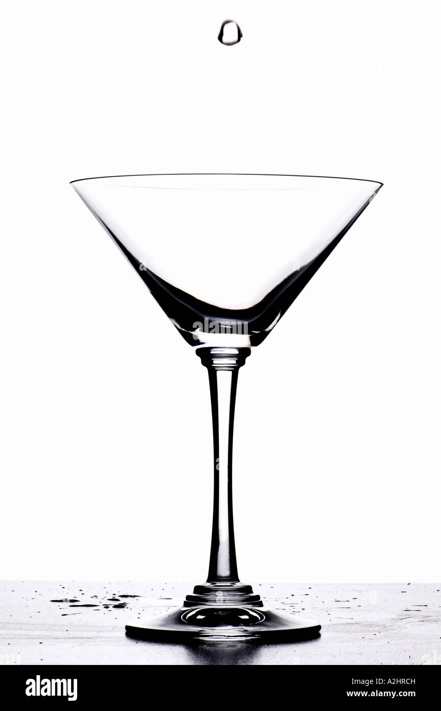 single drop of water falling into an empty glass on a white background ...