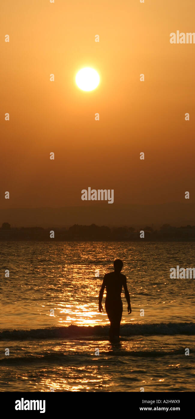 Man in silhouette shadow, wading out from the sea beach at sunset Stock ...