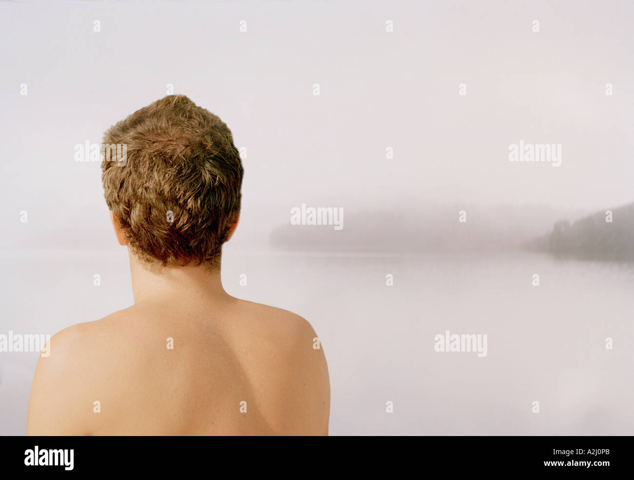 Back view of a young man looking over a misty lake, early morning Stock ...