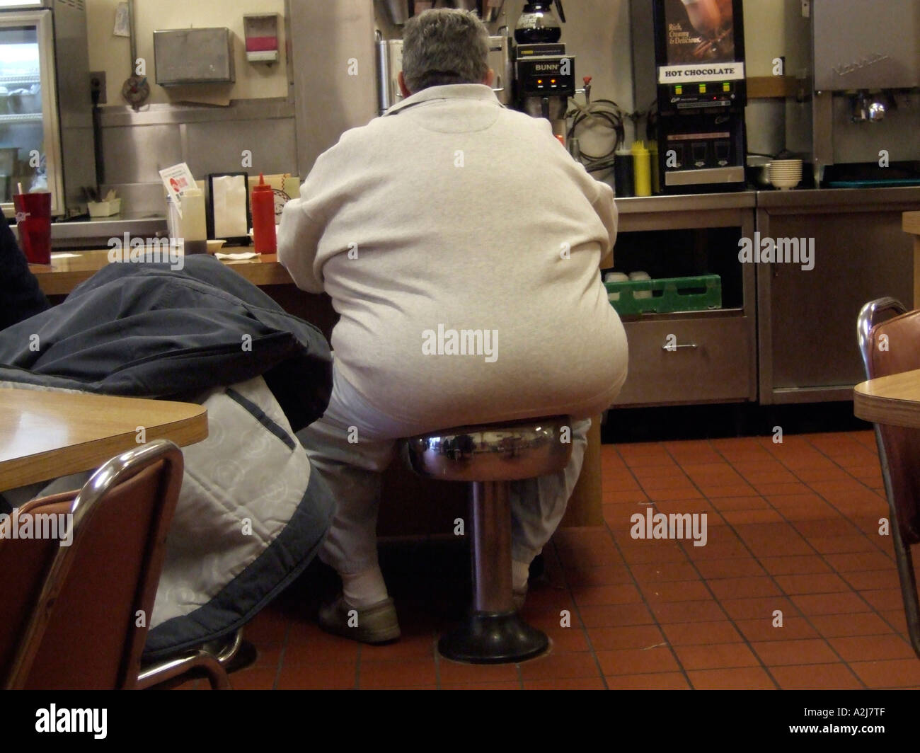 Fat obese over weight female sits at the counter inside a restaurant as ...