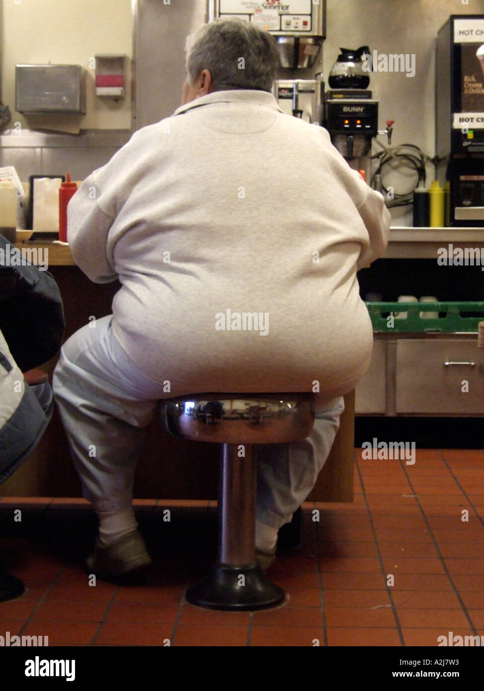 Fat obese over weight female sits at the counter inside a restaurant as ...