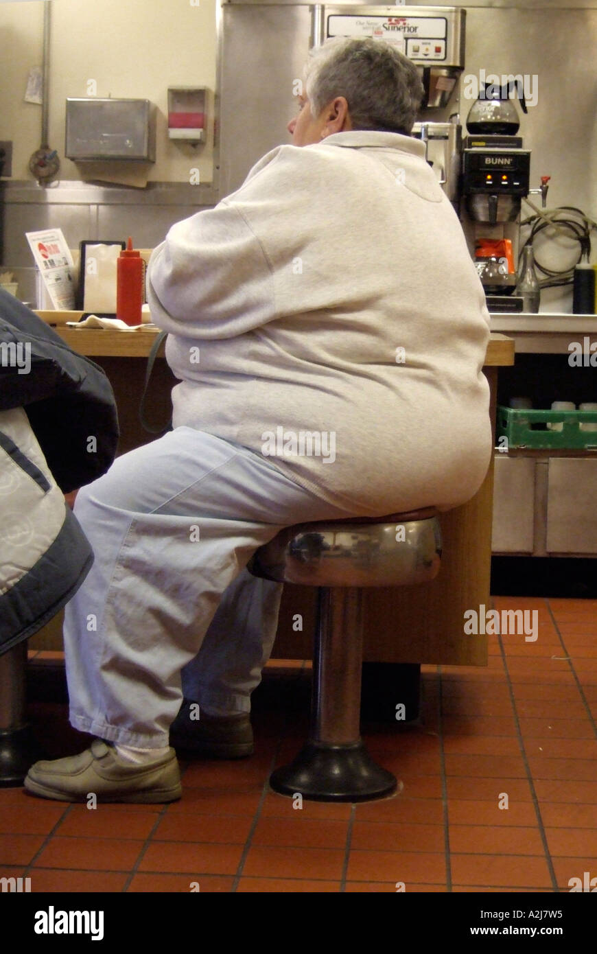 Fat obese over weight female sits at the counter inside a restaurant as ...