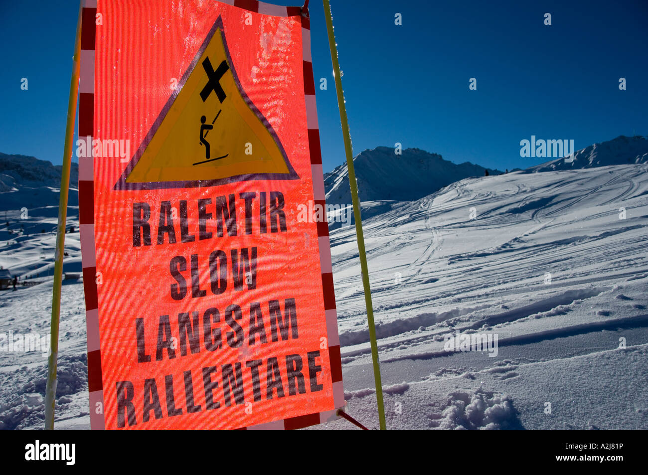 Red slow warning sign on ski piste crossing a drag lift track in the ...