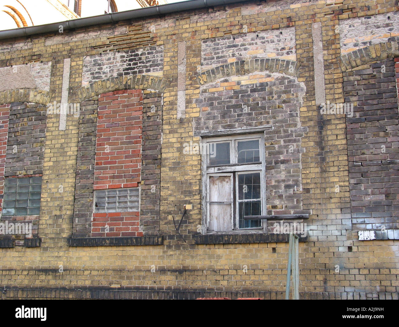 Brick wall with improvised repairs and window frame with closed off ...