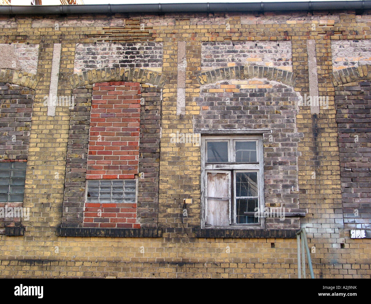 Brick wall with improvised repairs and window frame with closed off ...