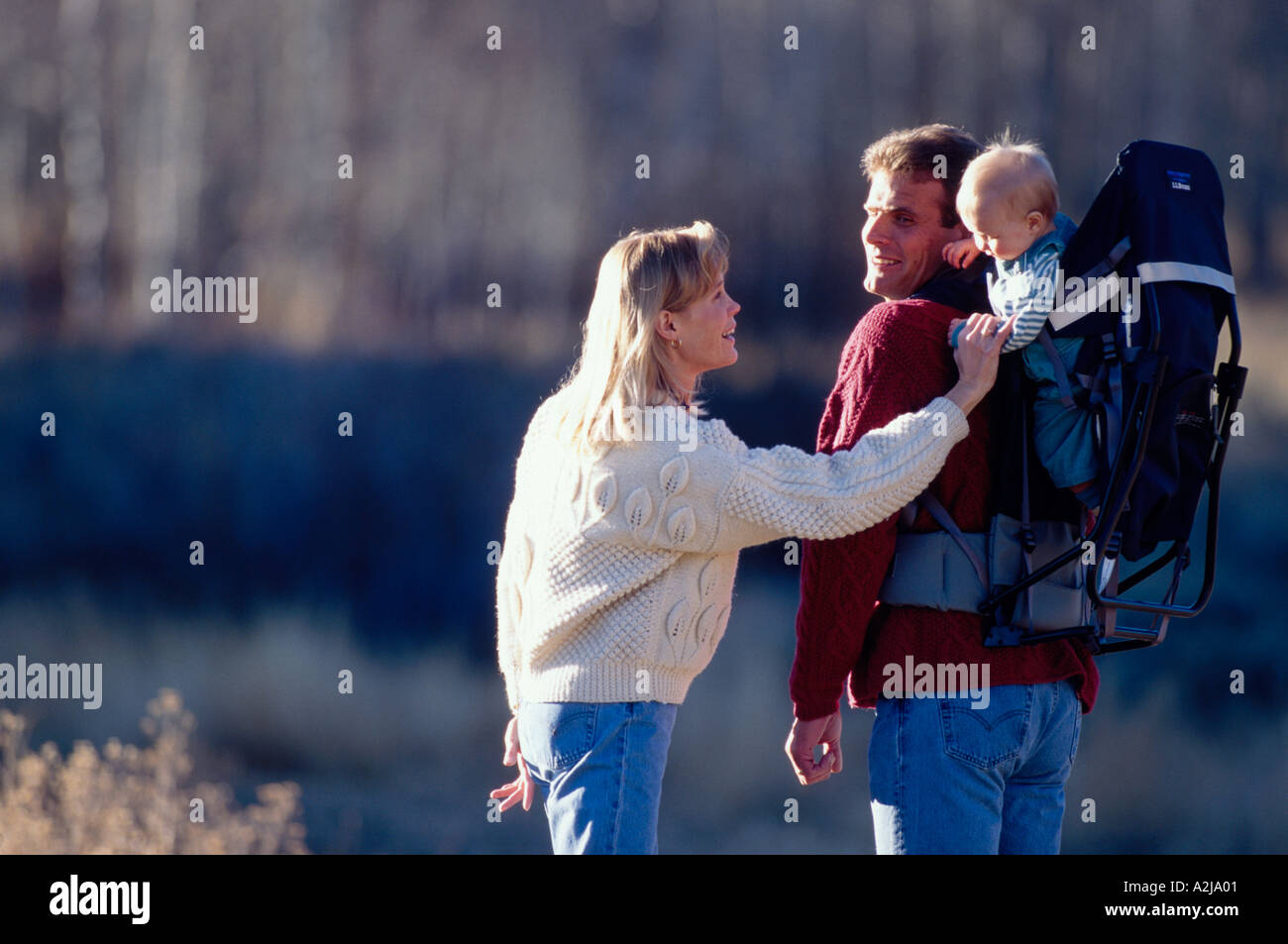 A mother pays attention to her small child who is being carried in a ...