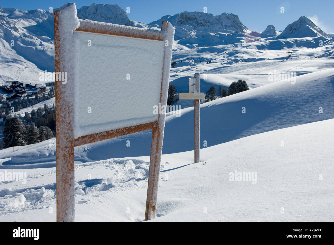snow covered sign board on a white snowfield with mountains and an ...