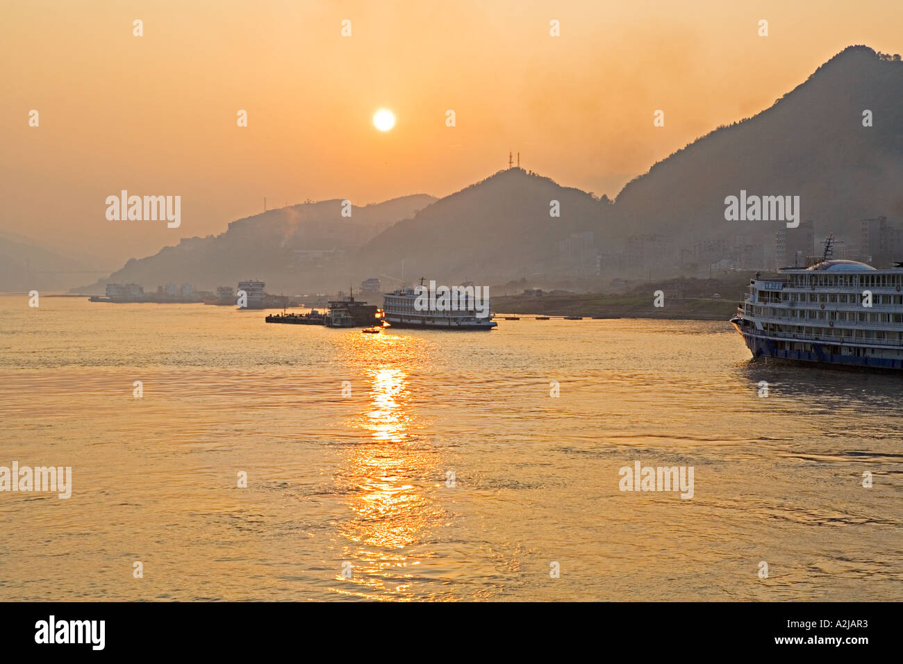 CHINA YANGTZE RIVER Cruise ships freighters and barges docked at sunset ...