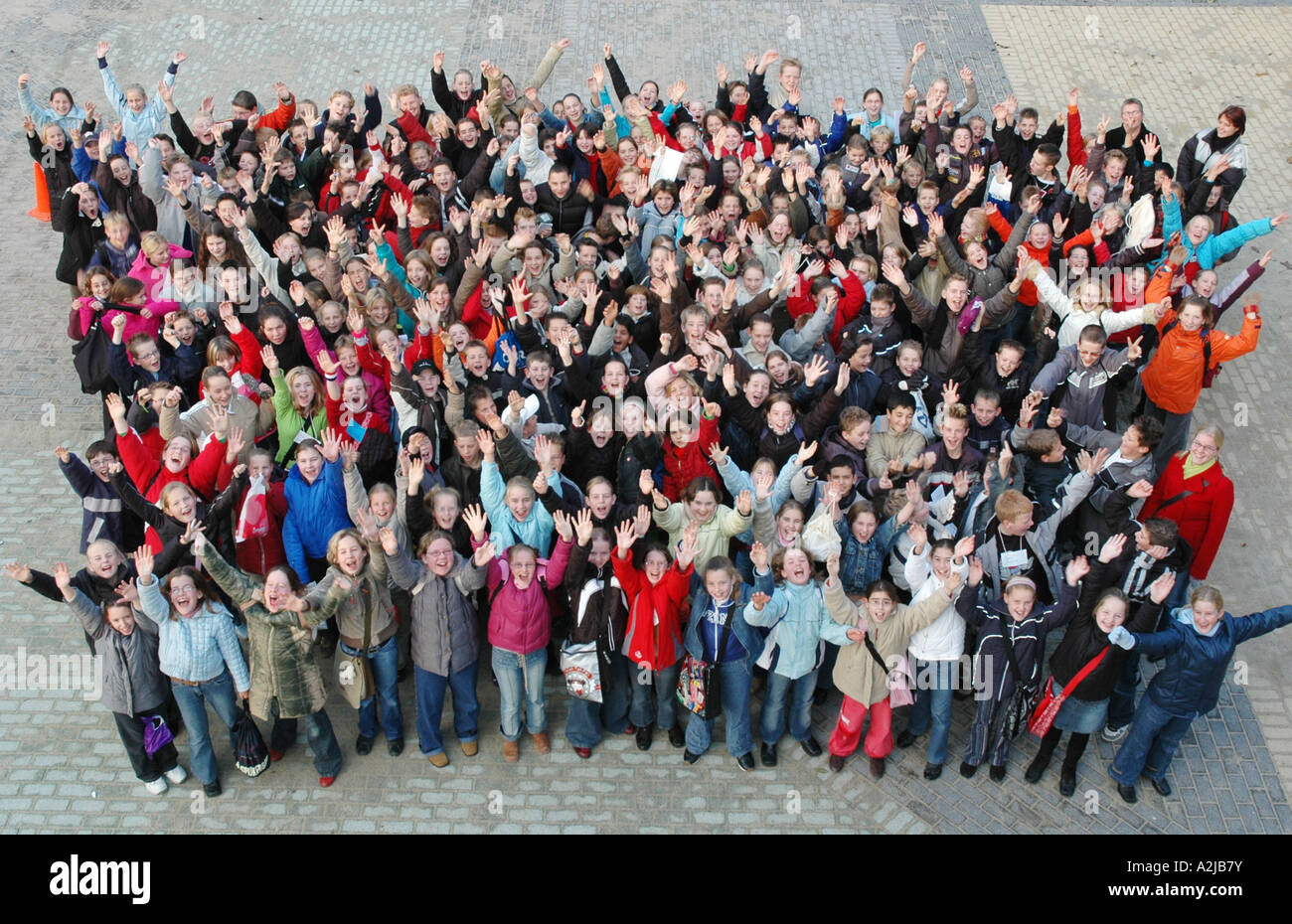 Large group of primary school children looking up and waving at the ...