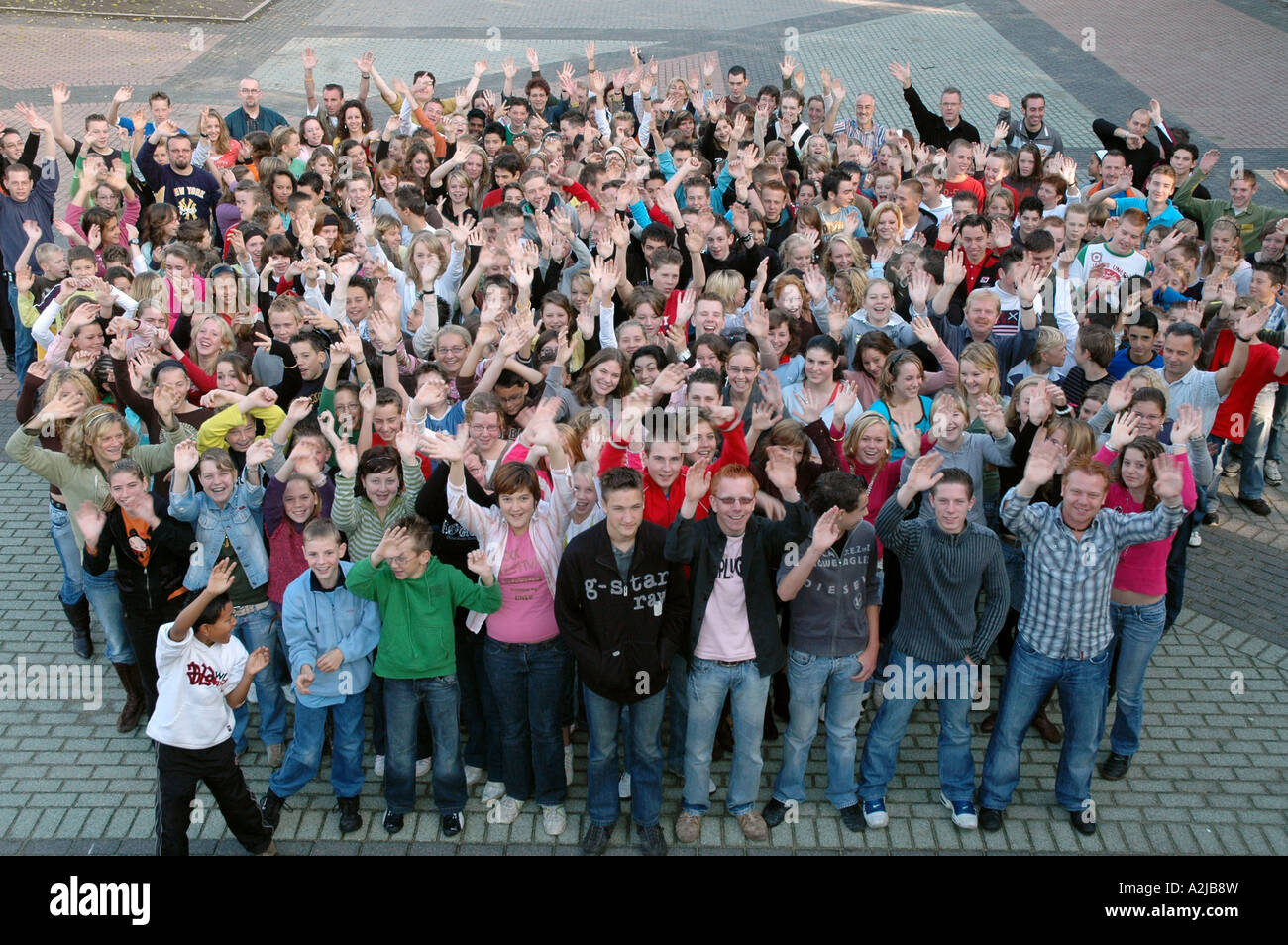 Large group of secondary school children looking up and waving at the ...