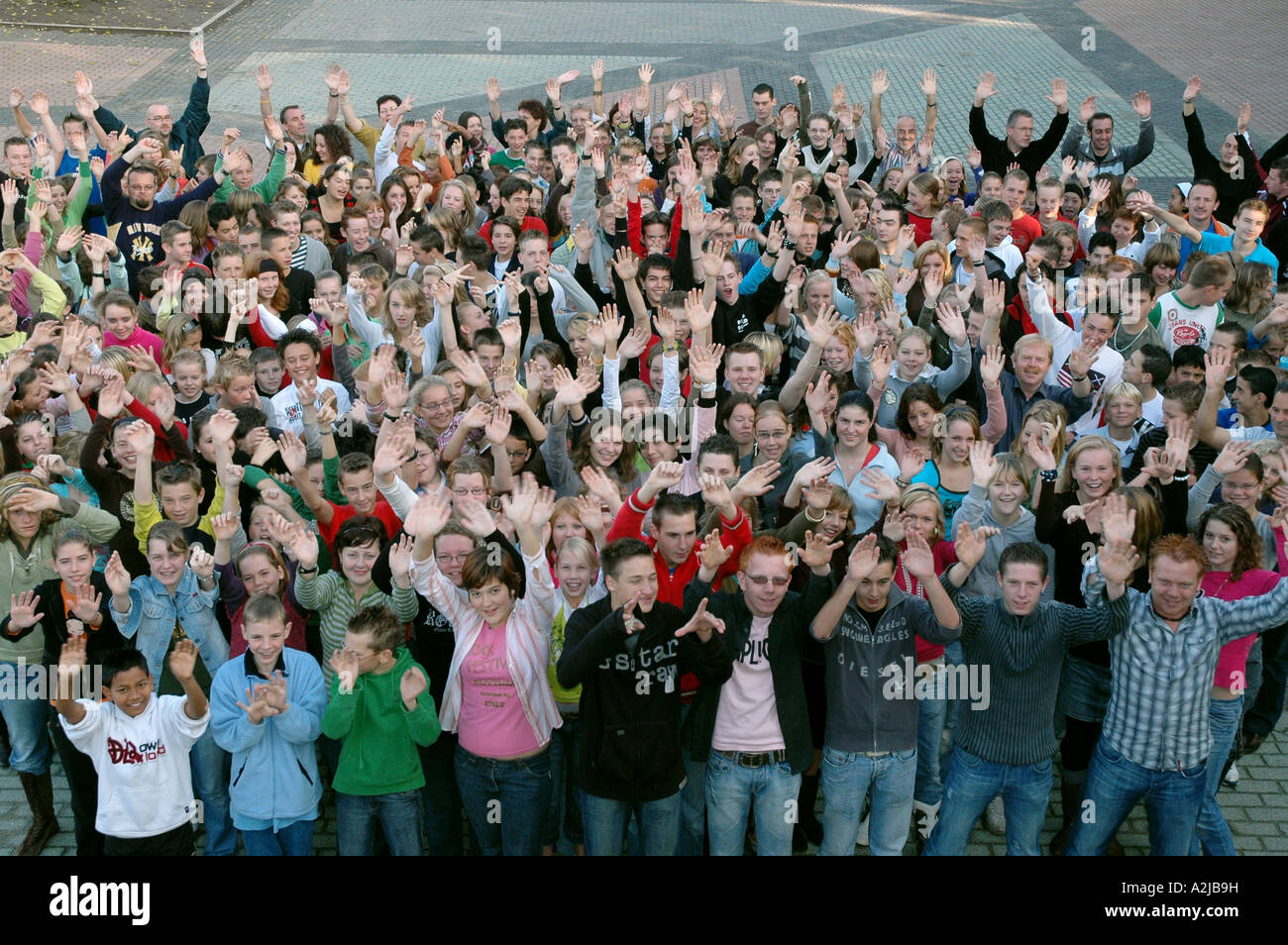 Large group of secondary school children looking up and waving at the ...