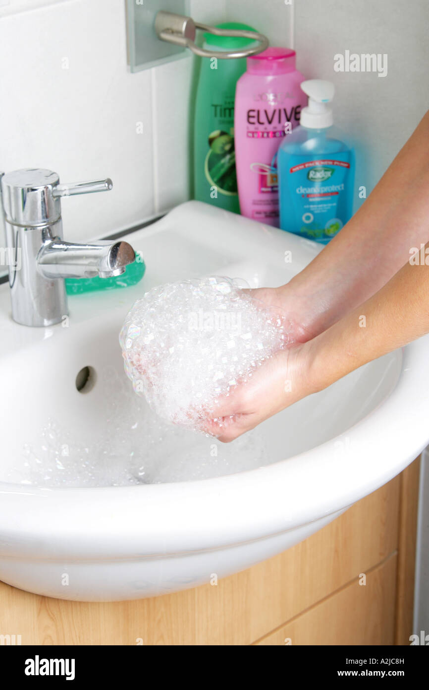Young Woman Washing Her Hands In A Bathroom Sink With Soap And Water ...