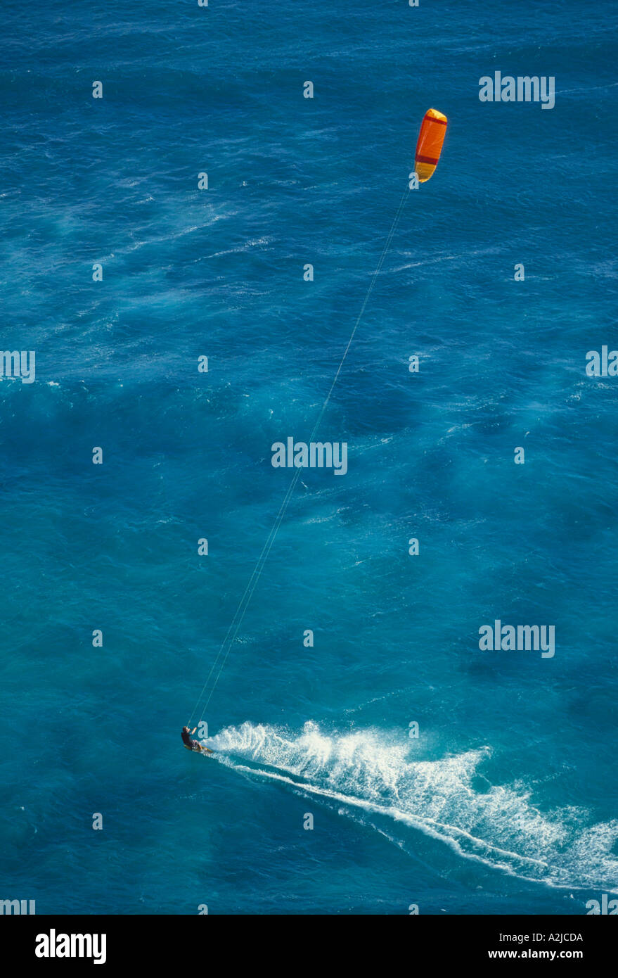Aerial view of a parasailer using a orange parawing to be pulled with ...