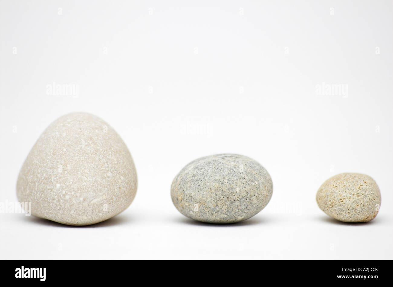 Three various sized pebbles on white background Stock Photo - Alamy