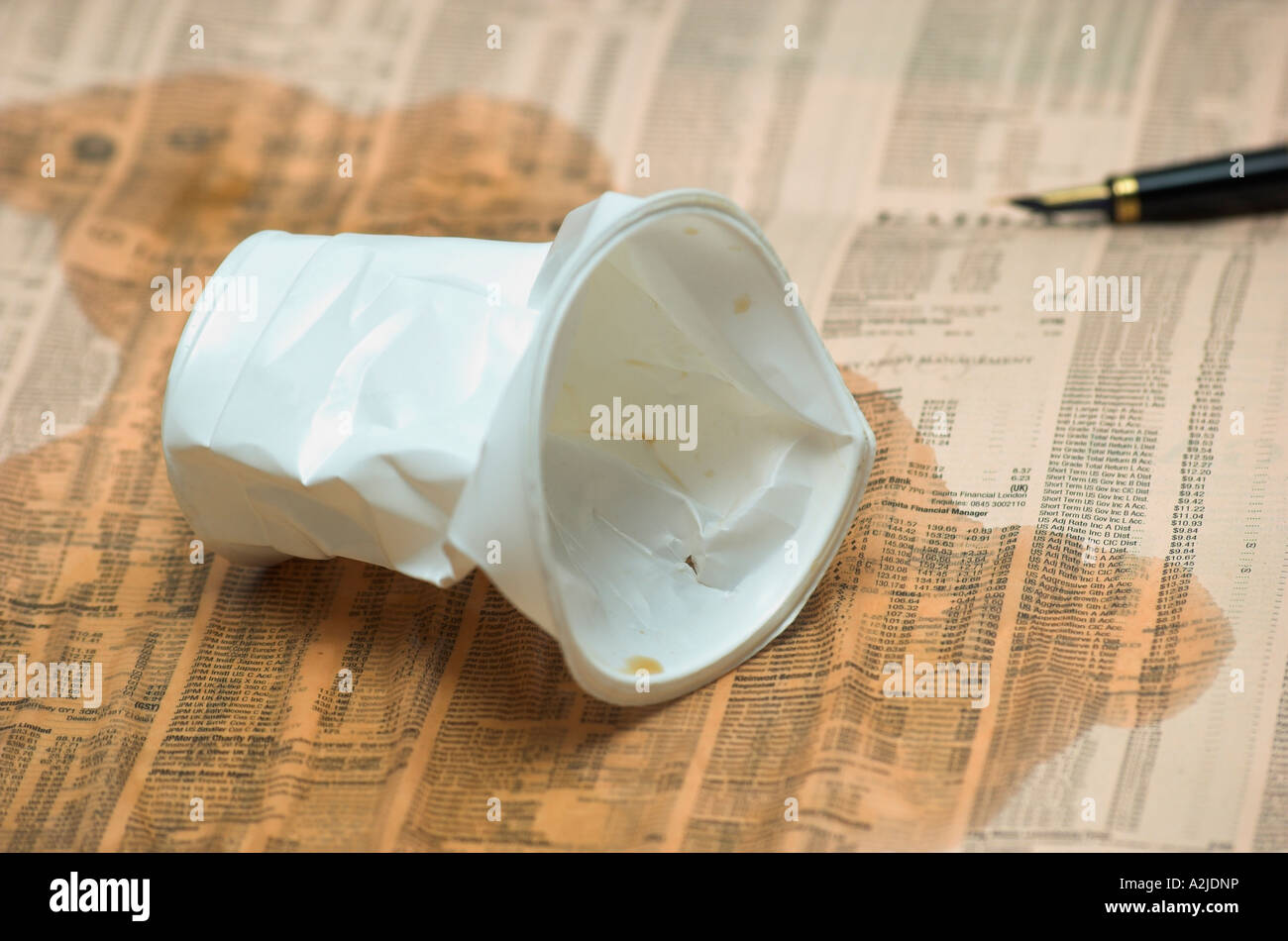 Fountain pen crushed coffee cup spilt coffee over financial newspaper ...