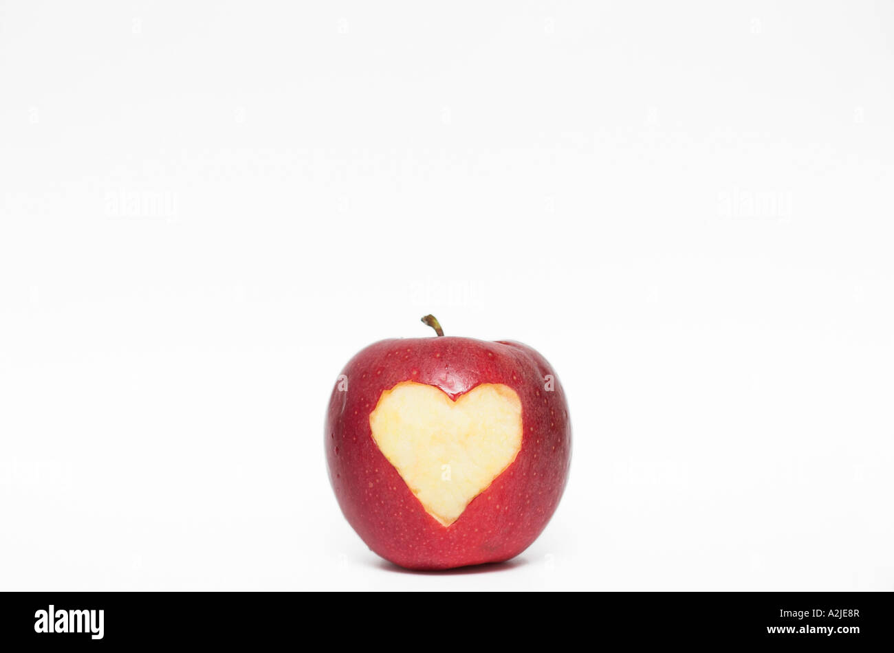 Heart shape symbol carved on red apple against white background Stock ...