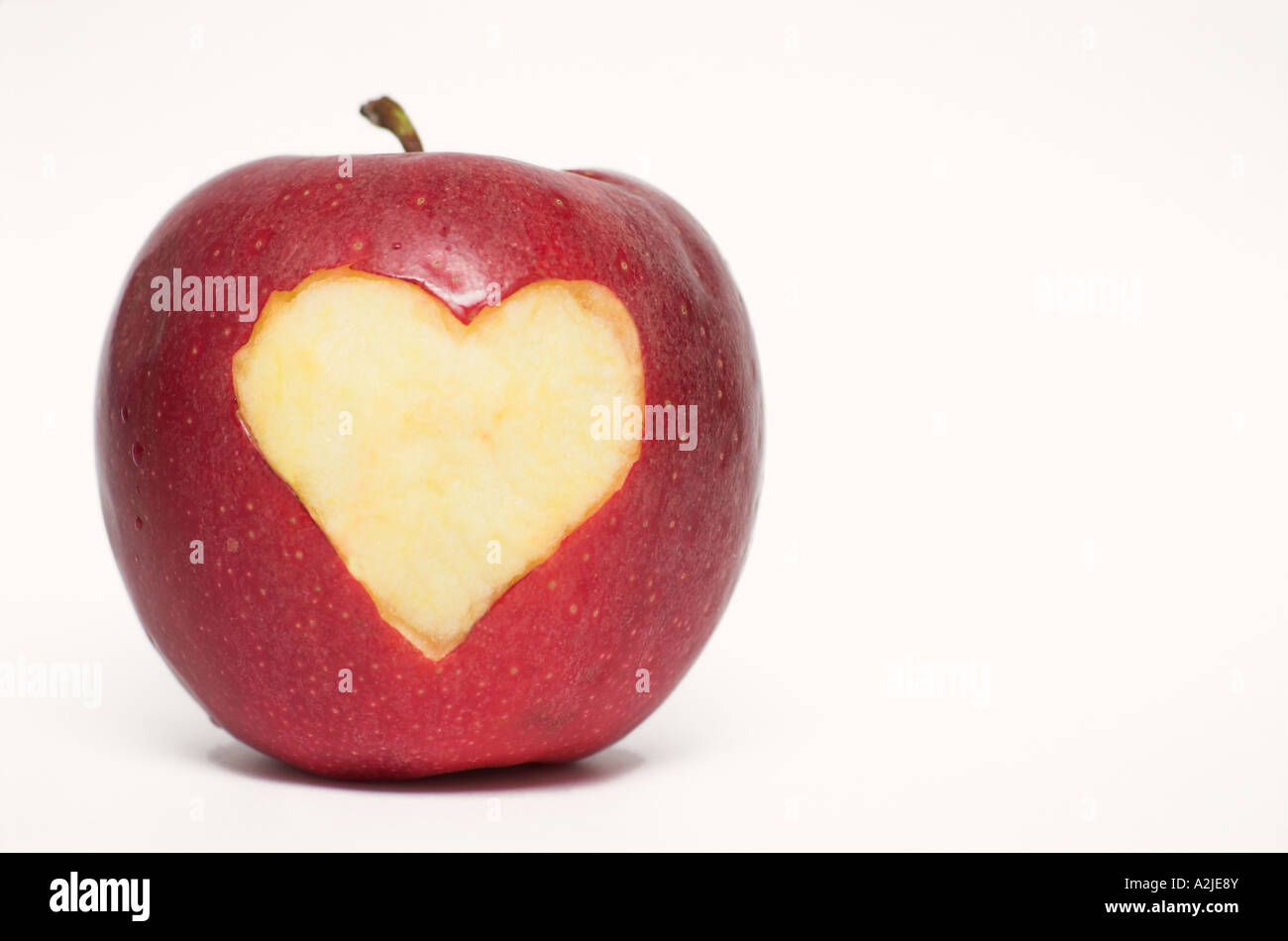 Heart shape symbol on red apple against white background Stock Photo ...