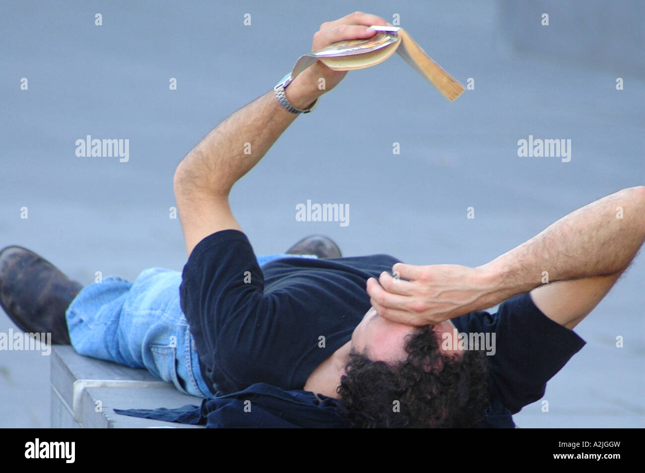A man lying down reading a book Stock Photo - Alamy