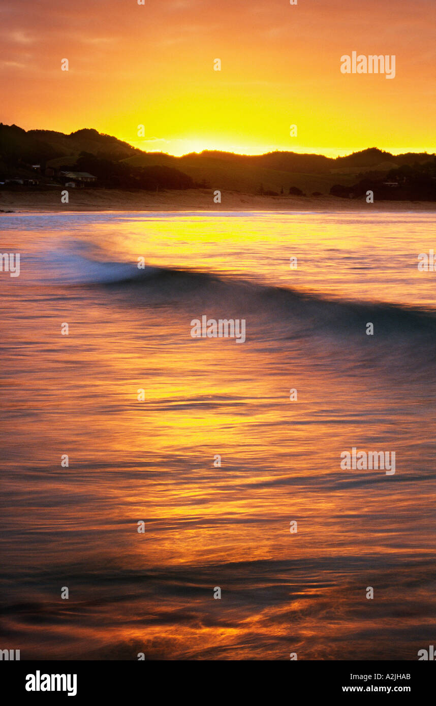 Golden red sunset reflects on ocean surface and breaking wave Stock ...