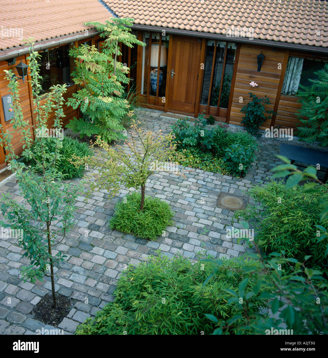 Aerial view of single storey house and paved courtyard with small trees ...