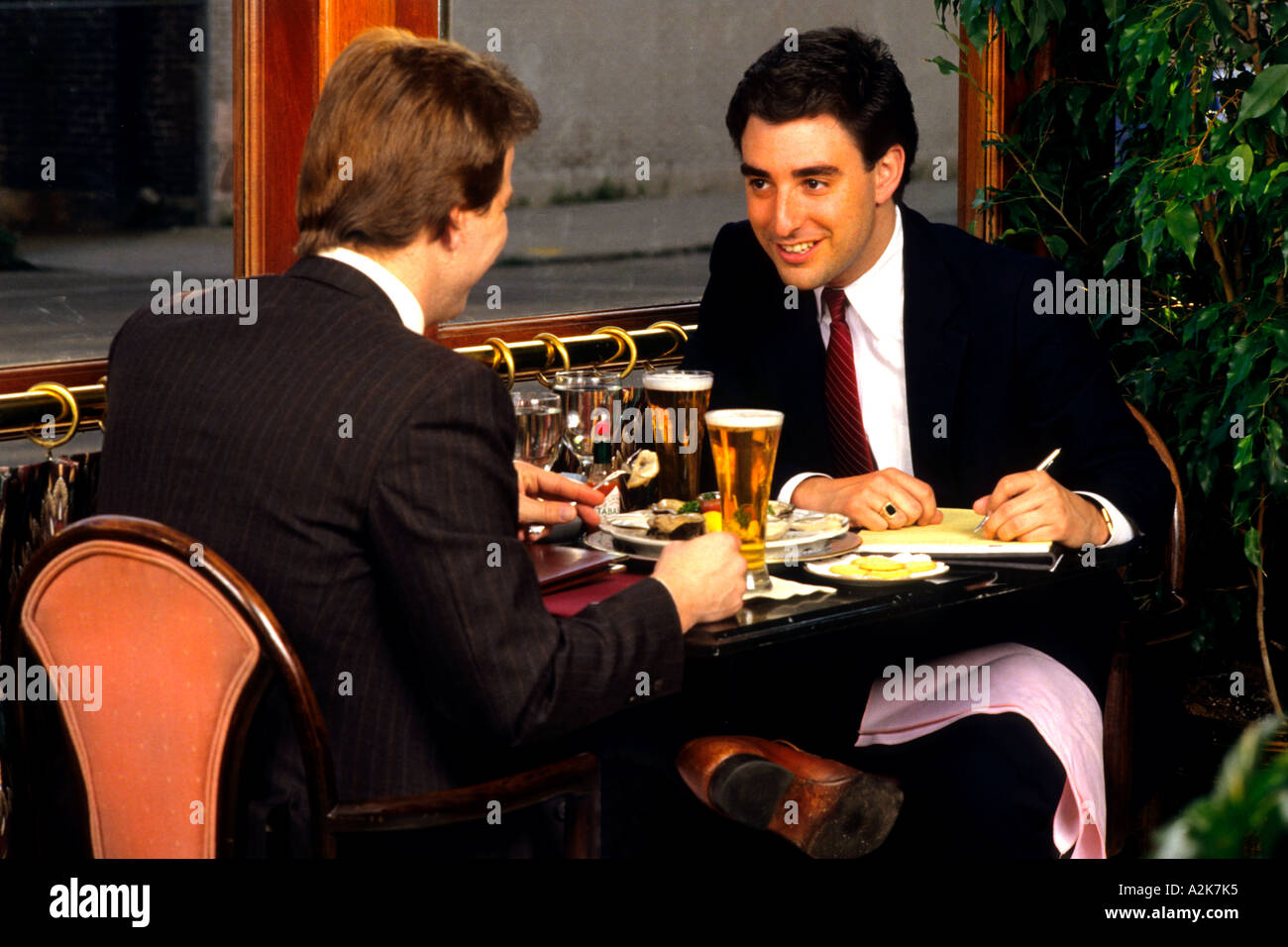 Two men having a power lunch with beer at lunch restaurant discussing ...