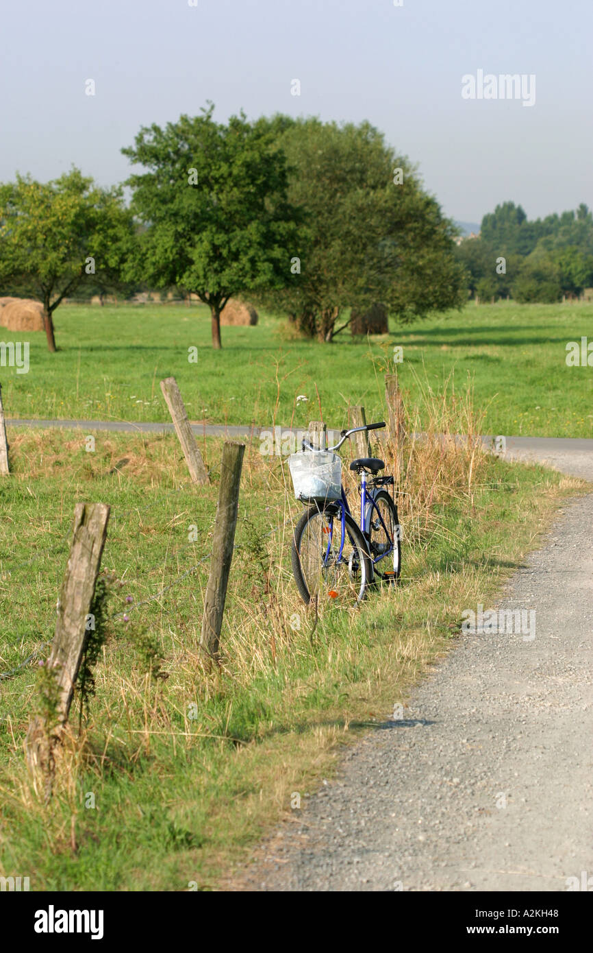 A bicycle is reclining on a fence near a way Stock Photo - Alamy