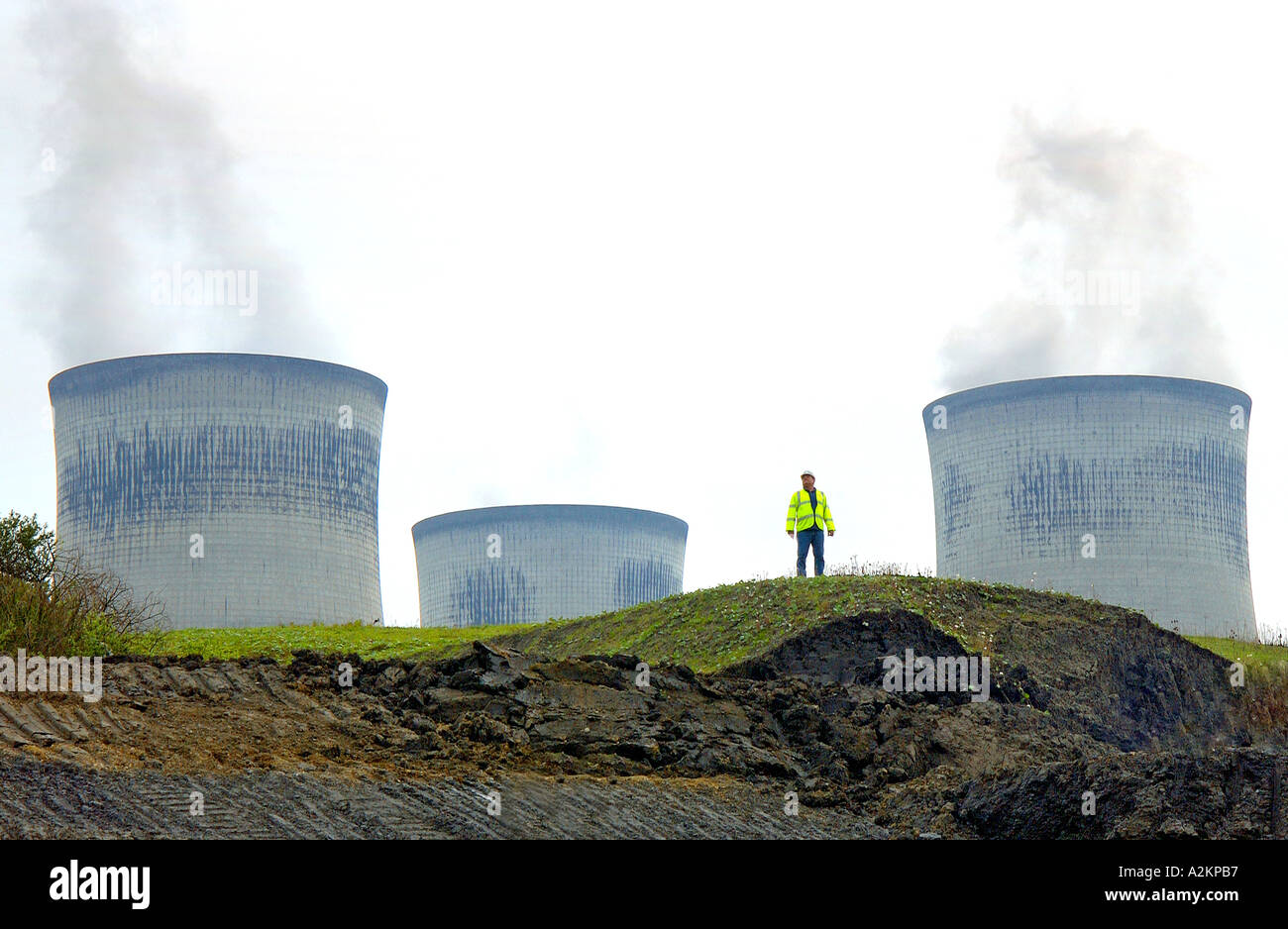Man standing at top of land fill site infront of cooling towers Cooling ...