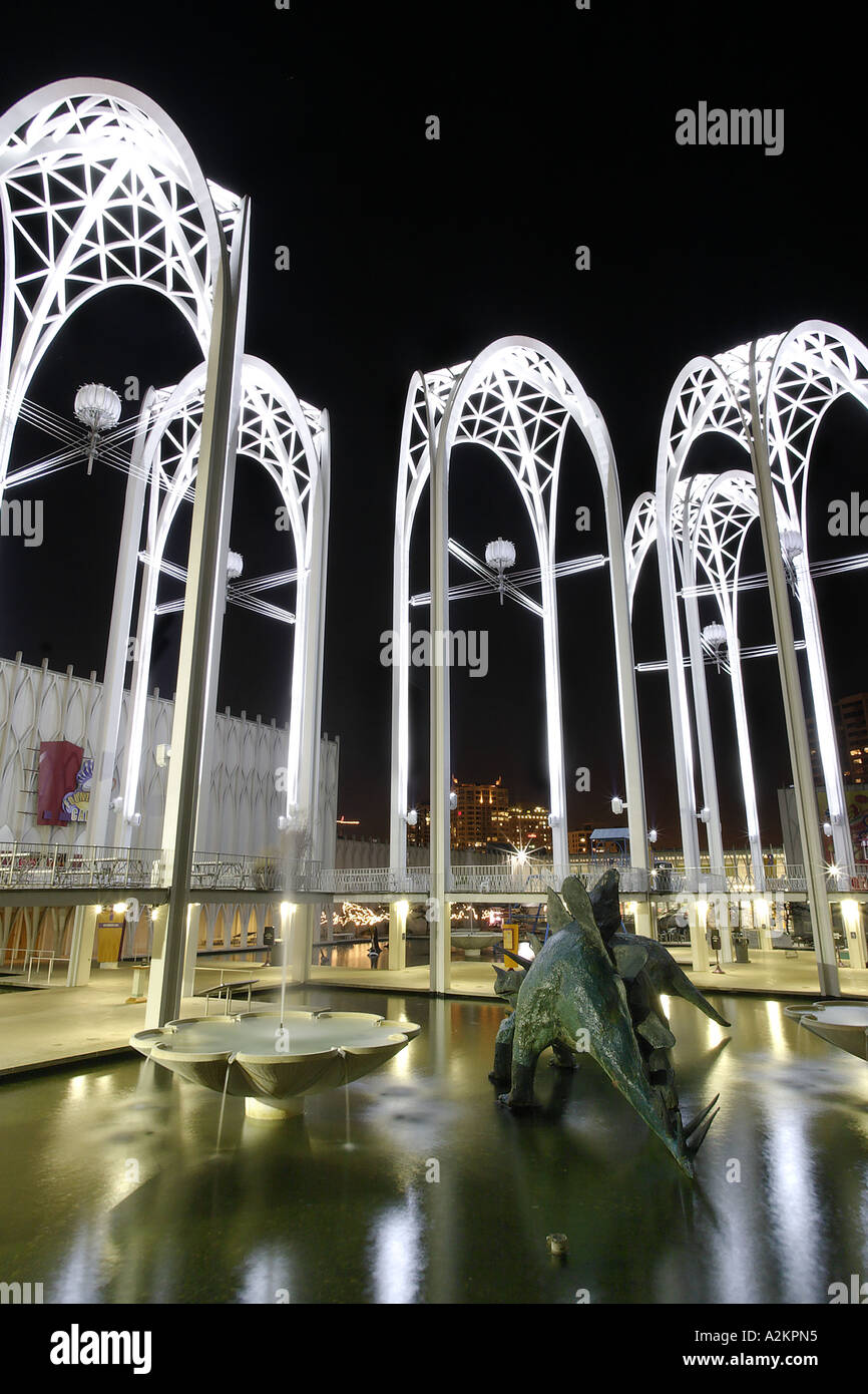 Nighttime scene of dinosaur statues wading in pools below arches at ...