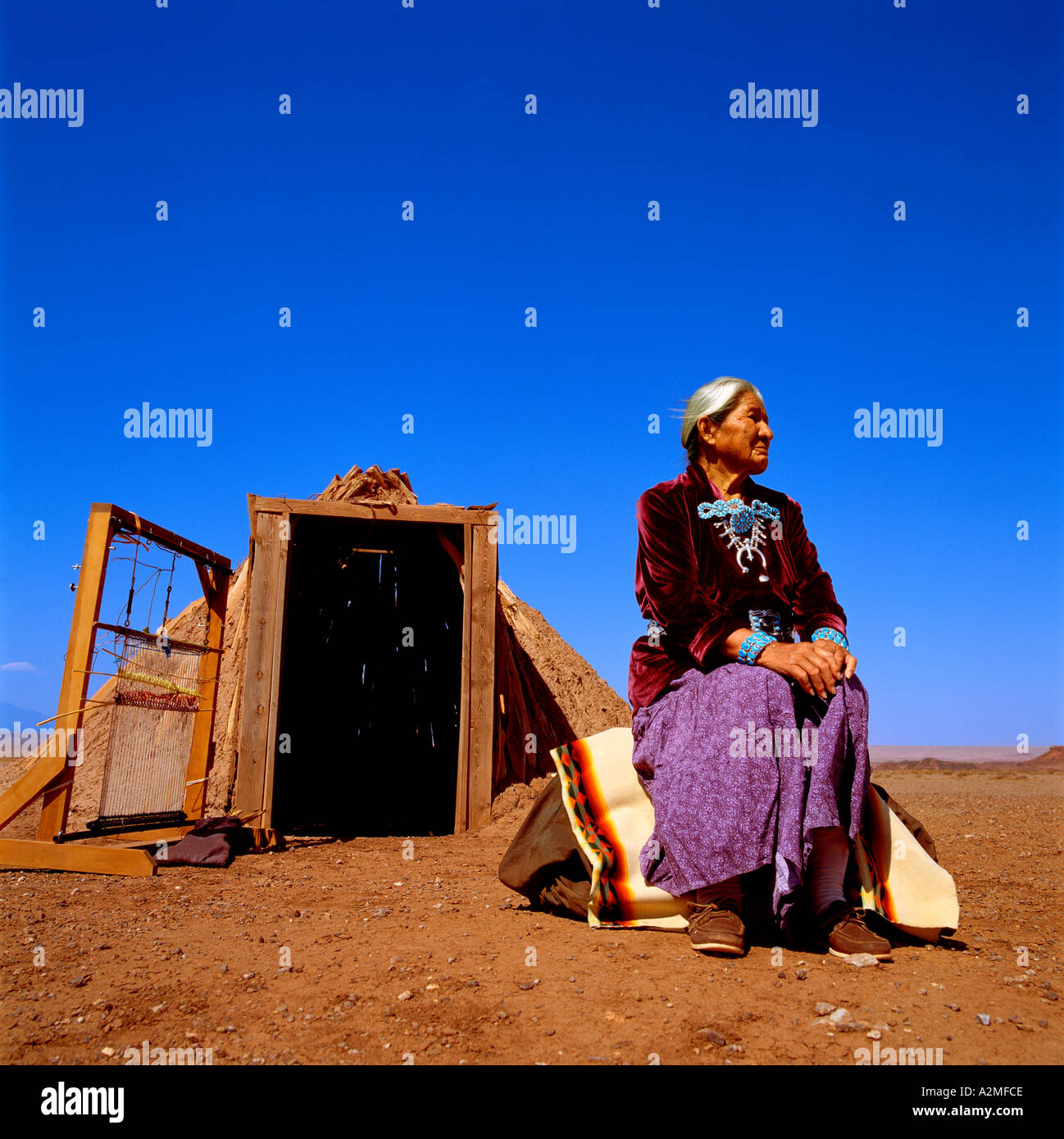 portrait of an old Navajo weaver in front of a traditional male hogan ...