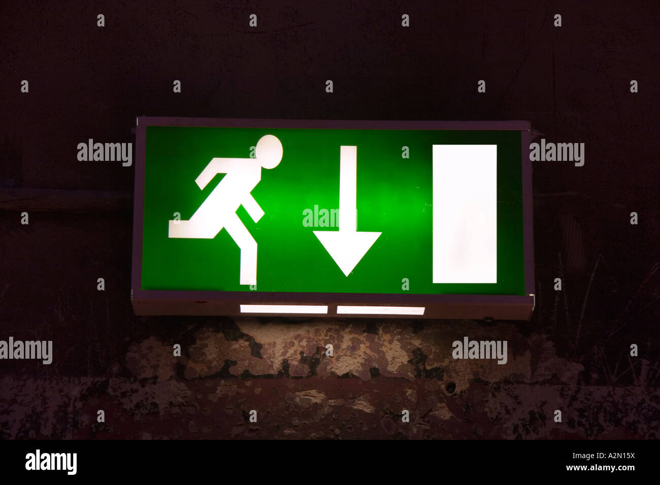 Illuminated green and white exit sign showing a figure running and an ...