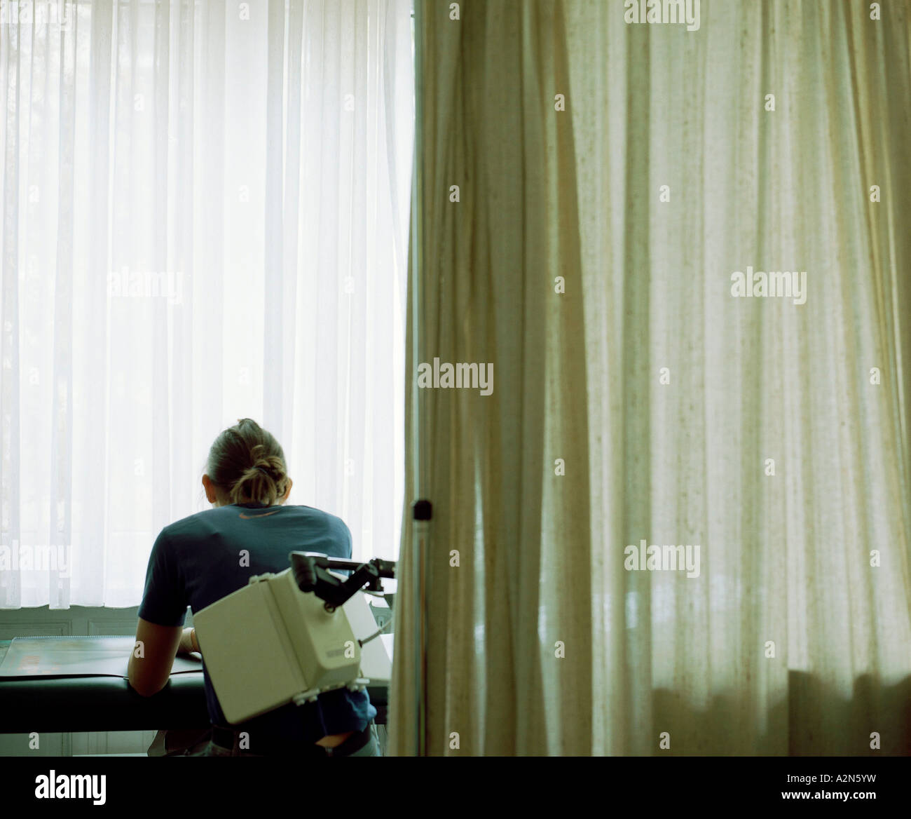 Rear view of young woman undergoing fluoroscopy medical examination ...