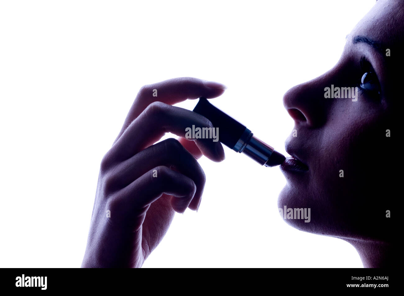 Young woman applying lipstick on lips, side view Stock Photo - Alamy