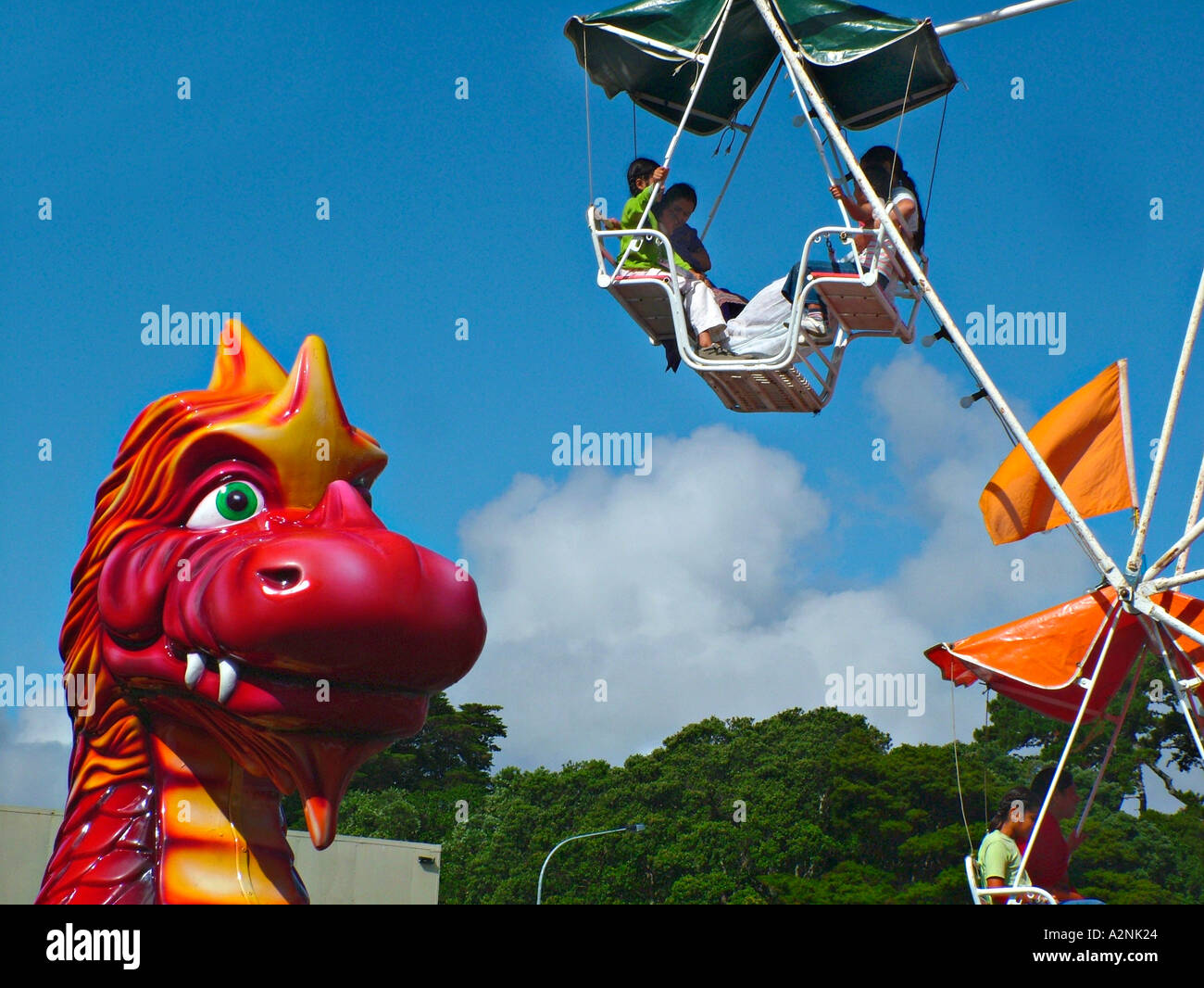 Giant red dragon and show ground rides against blue sky at a funfair ...