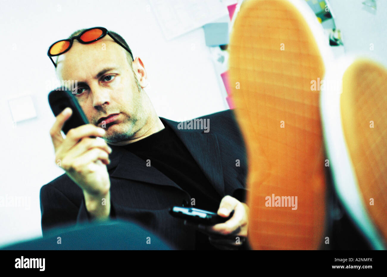 Young man using mobile phone and PDA in office Stock Photo - Alamy