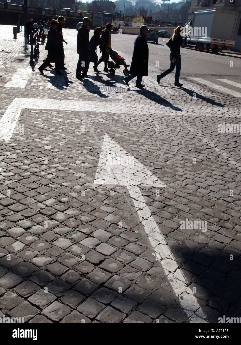 silhouette of people in background crossing cobbled street at ...