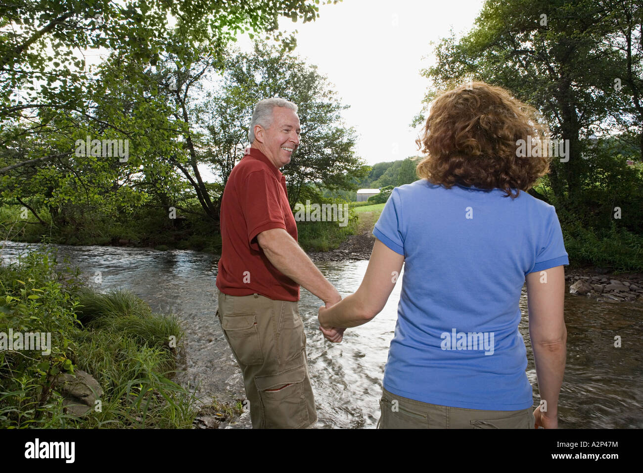 Mature couple crossing a stream Stock Photo - Alamy