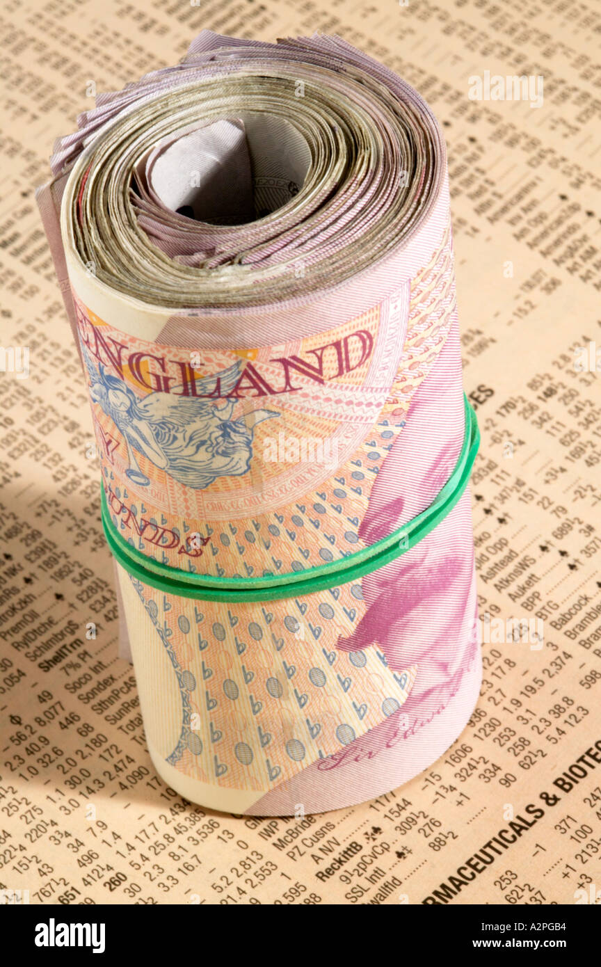 Roll of English twenty pound currency notes on stock market price page ...