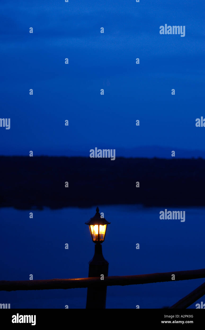 A small lantern lights the night at a lakeside resort. Vertical Stock ...