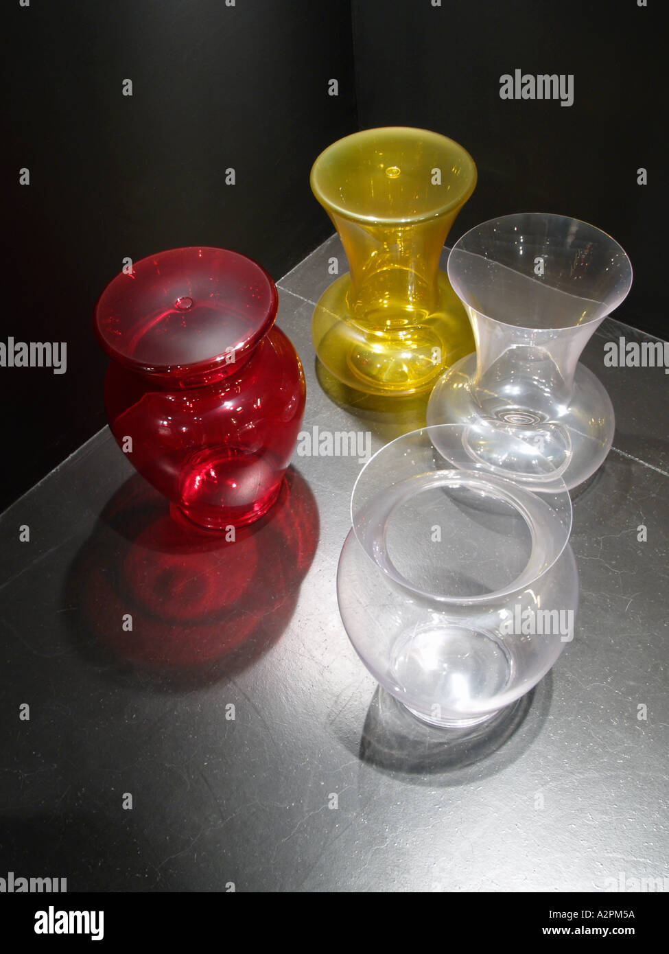 colored design vases and stools standing on the floor in a matte black ...