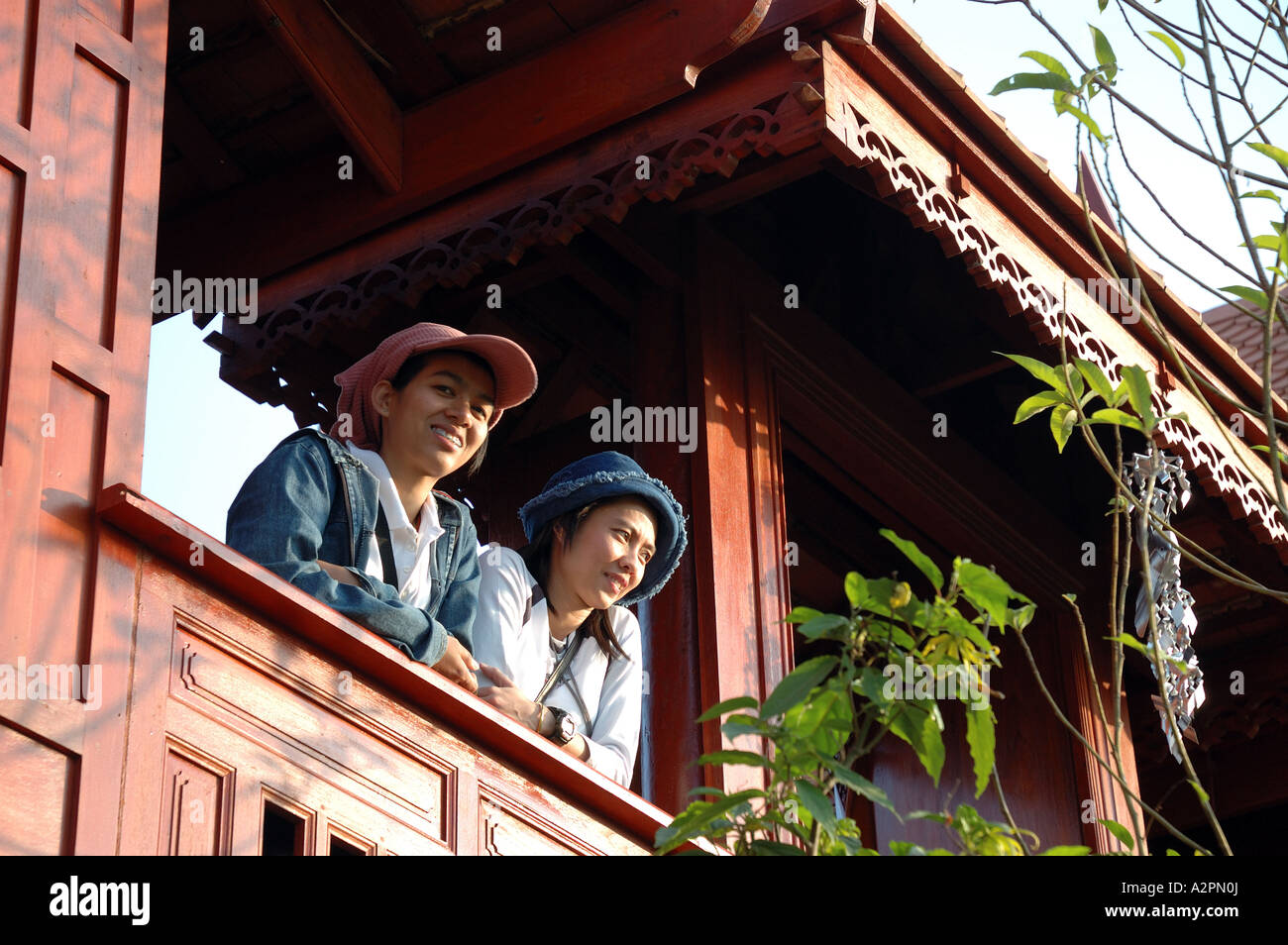 Girls looking out of a window in a wooden Thai house Stock Photo - Alamy