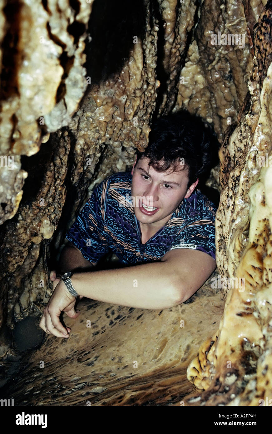 Man crawling through hole on tourist route at far end of Cango Cave ...