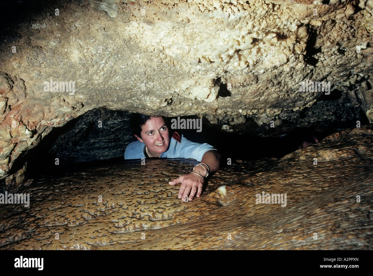 Female crawling through hole on tourist route at far end of Cango Cave ...