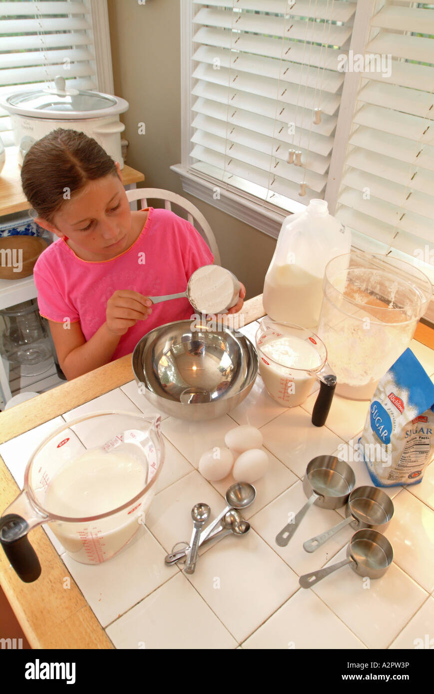 10 year old girl follows a recipe for pancakes She is measuring flour ...