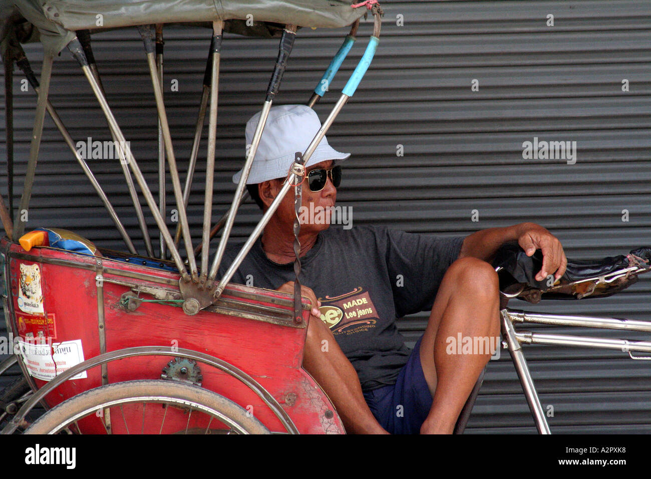 Bicycle rickshaw driver relaxing on the side of the road, Chiang Mai ...
