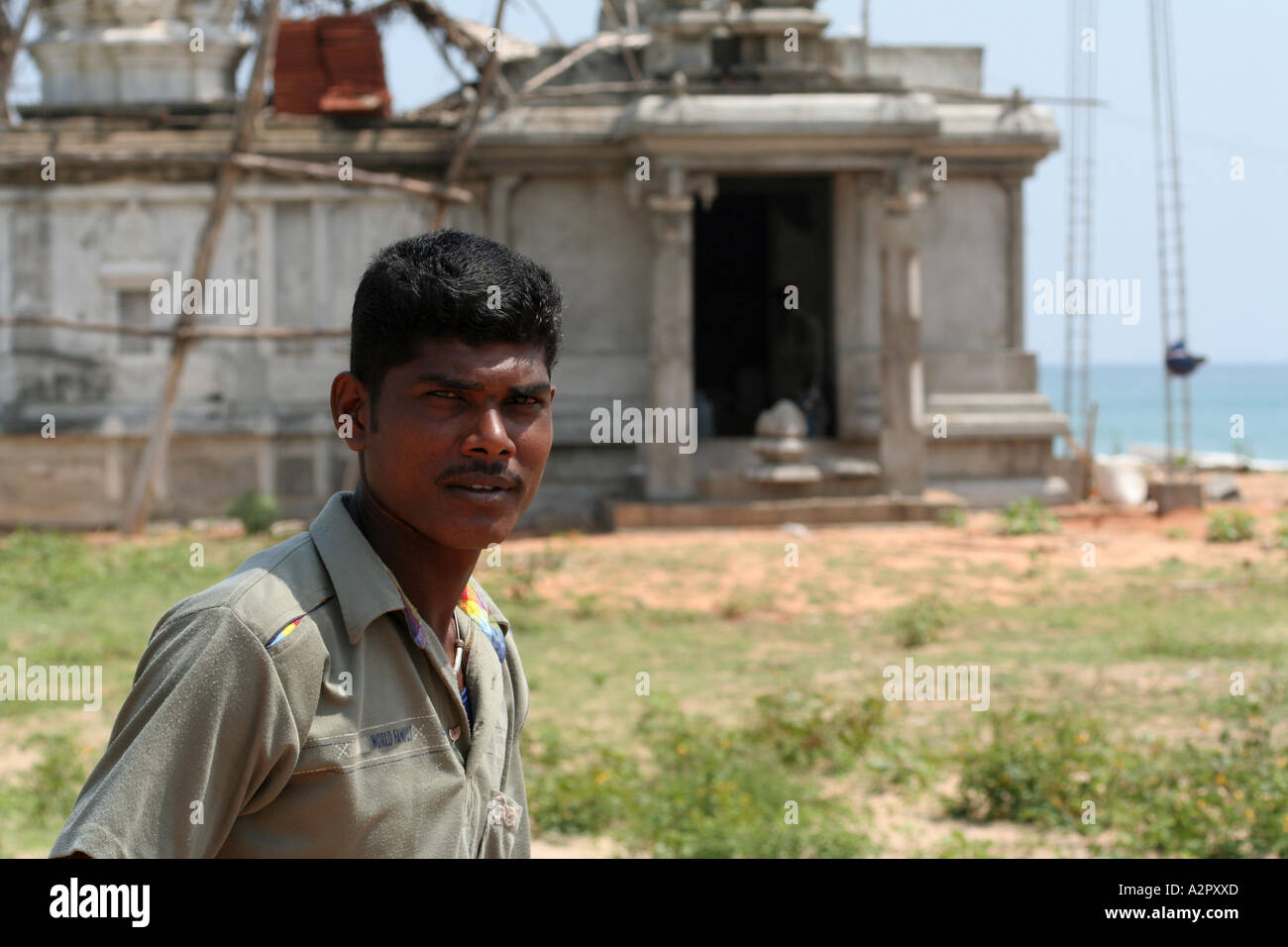 Young tamil man in front of restoration work on a hindu temple ...
