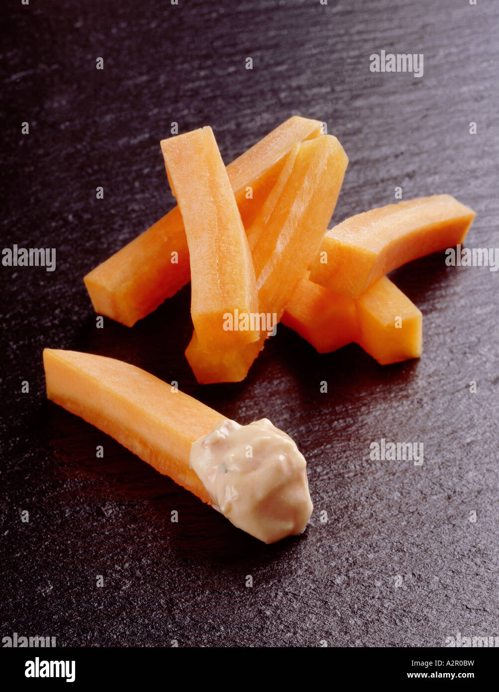 Carrot strips with a dip on black slate background Stock Photo - Alamy
