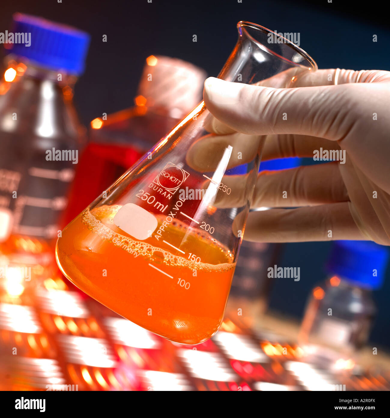 Beaker in Hand with Orange Liquid Stock Photo - Alamy