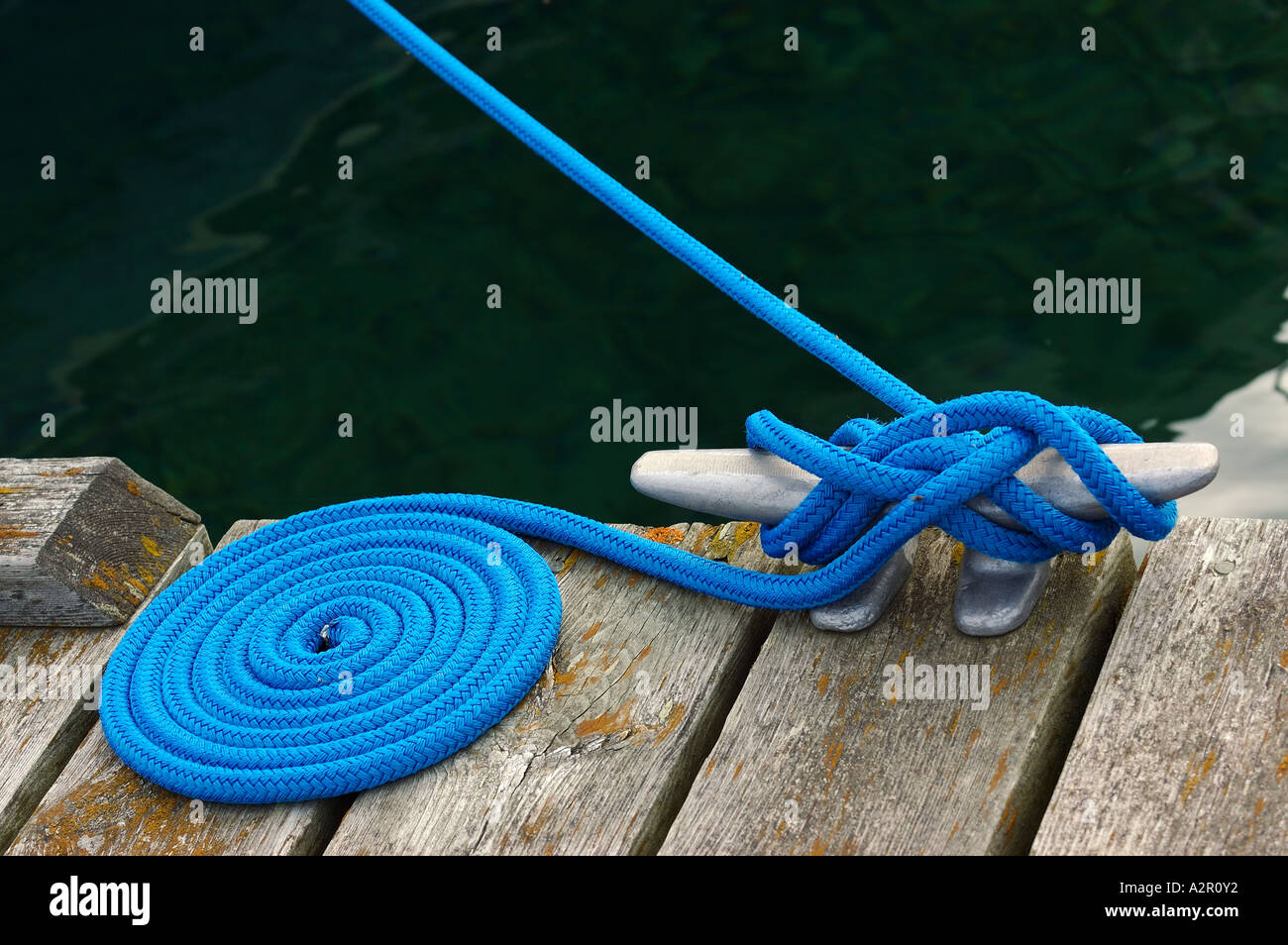 Coiled blue rope tying a boat to the dock Stock Photo - Alamy