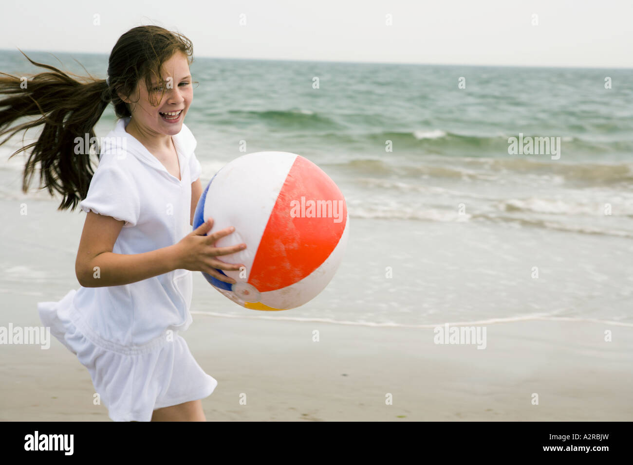 Girl runs with beach ball at the beach Stock Photo - Alamy